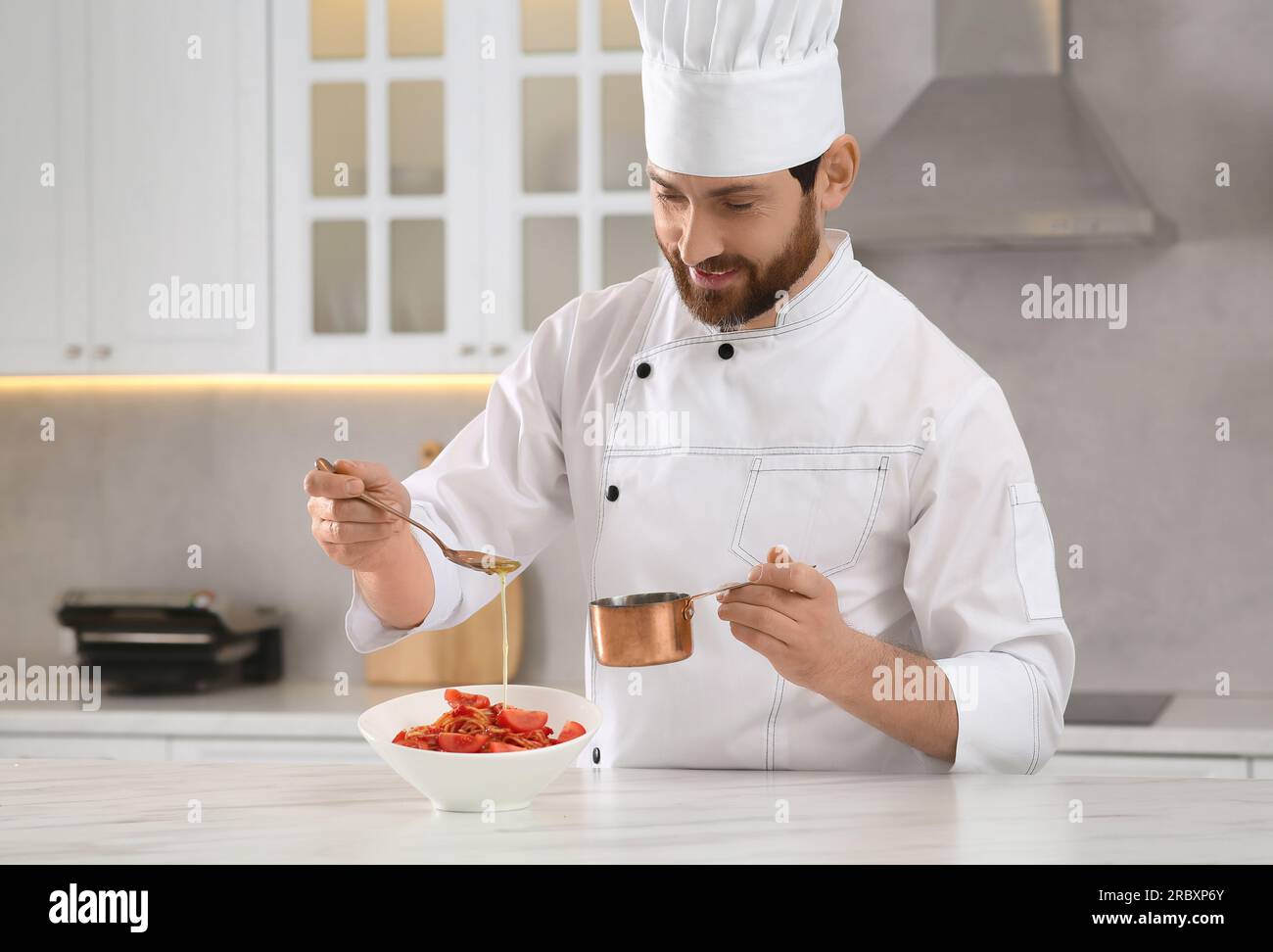 Professional chef pouring sauce into delicious spaghetti at marble ...
