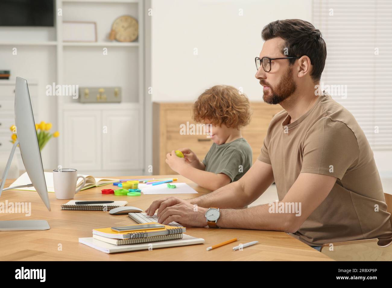 Man working remotely at home. Father using computer while his son ...