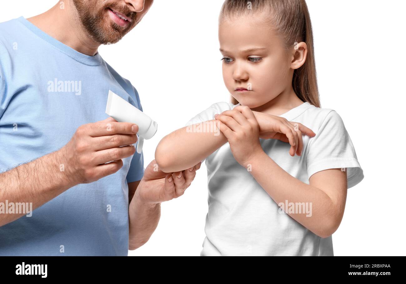 Father applying ointment onto his daughter's elbow on white background ...
