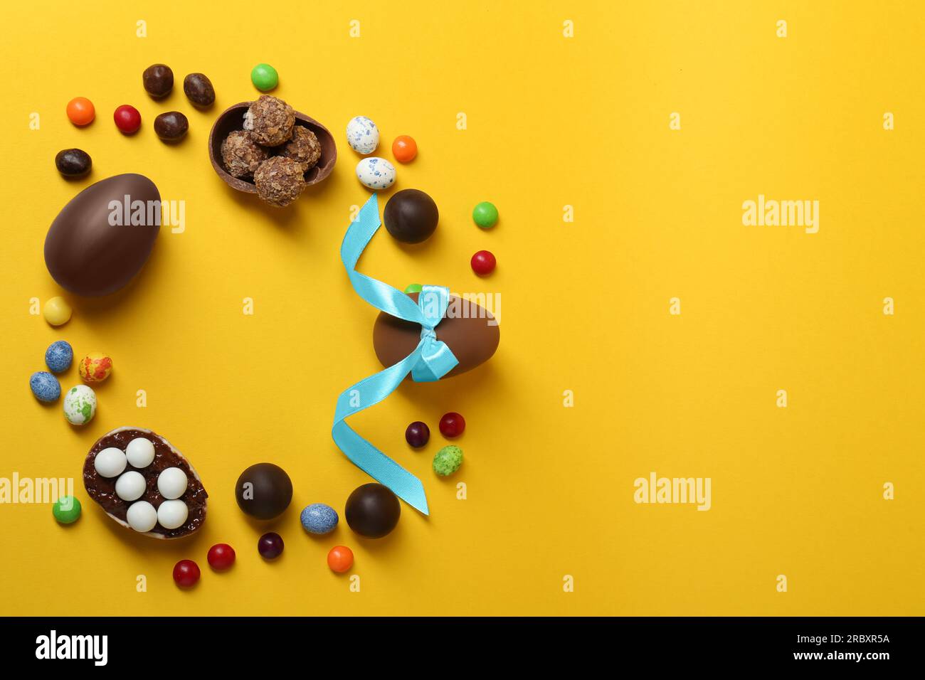 Frame of chocolate eggs and candies on yellow background, flat lay ...