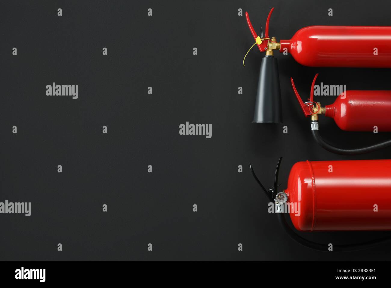 Different fire extinguishers on black background, flat lay. Space for ...