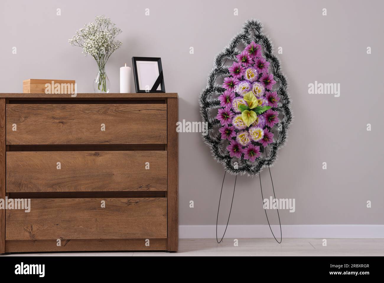 Wreath of plastic flowers and frame with black ribbon, burning candle ...