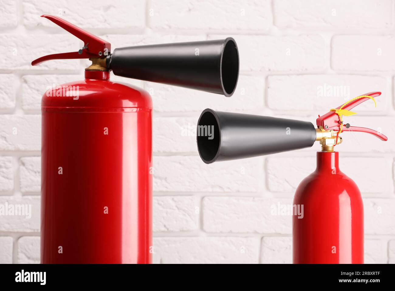 Fire extinguishers against white brick wall, closeup Stock Photo - Alamy