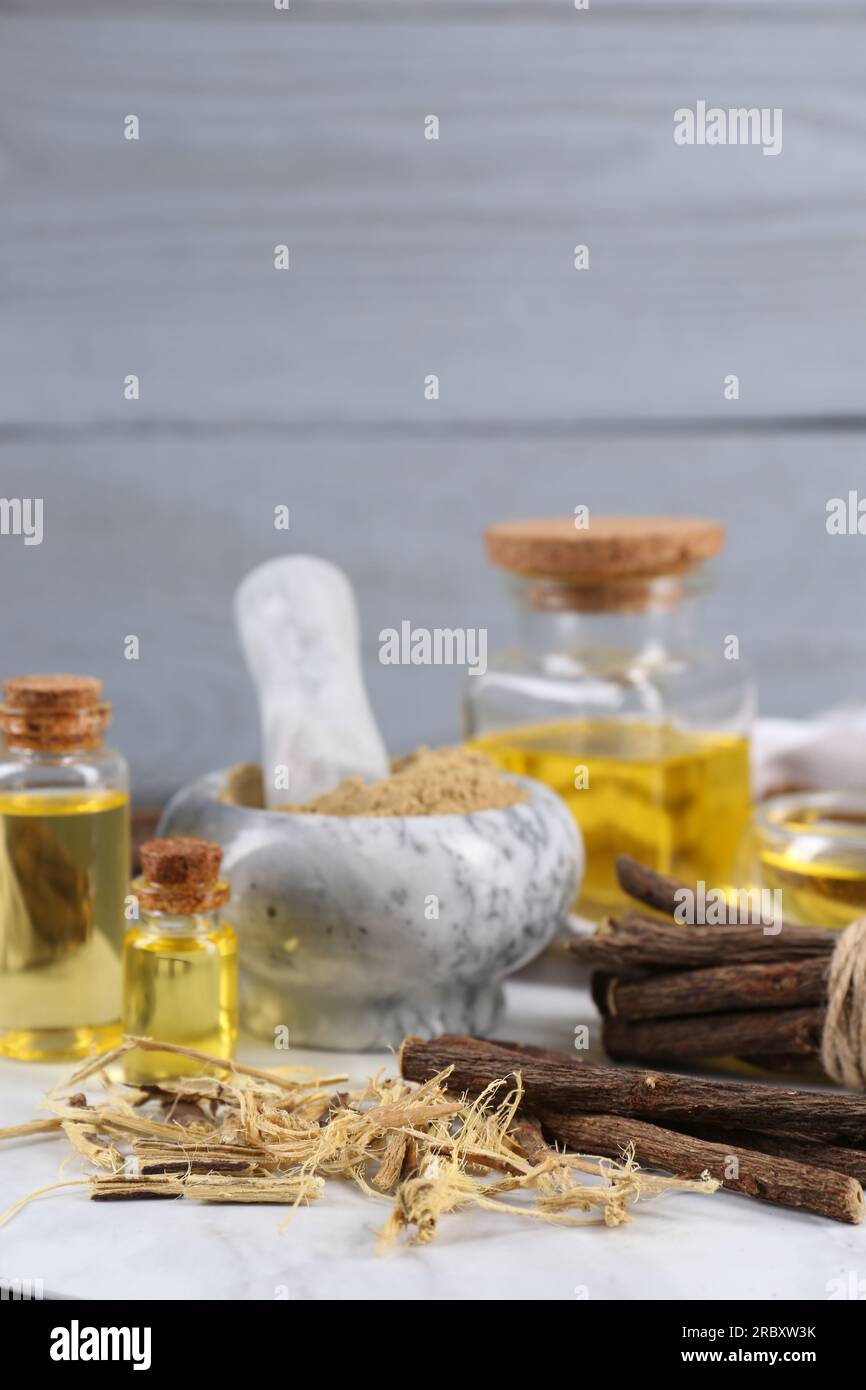 Dried sticks of licorice roots, shavings and essential oil on white ...