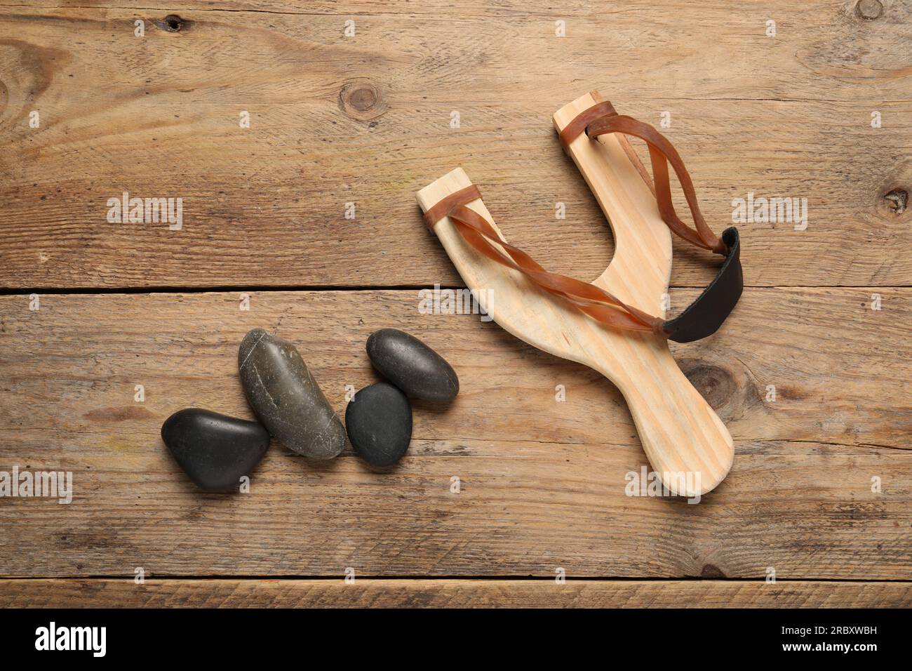 Slingshot with stones on wooden background, flat lay Stock Photo - Alamy