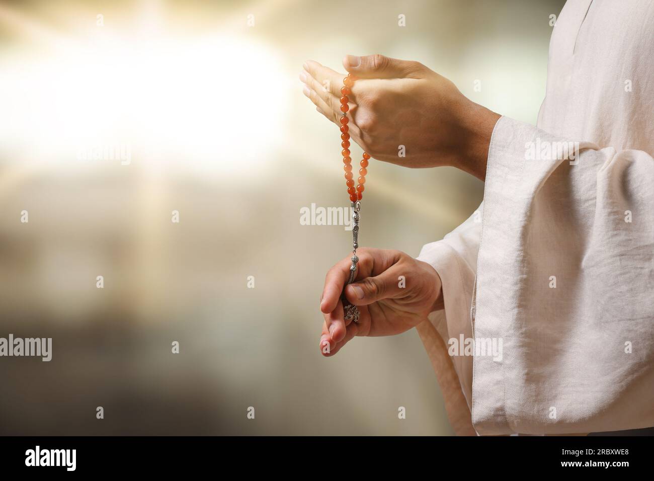 Muslim man with misbaha praying on blurred background, closeup. Space ...