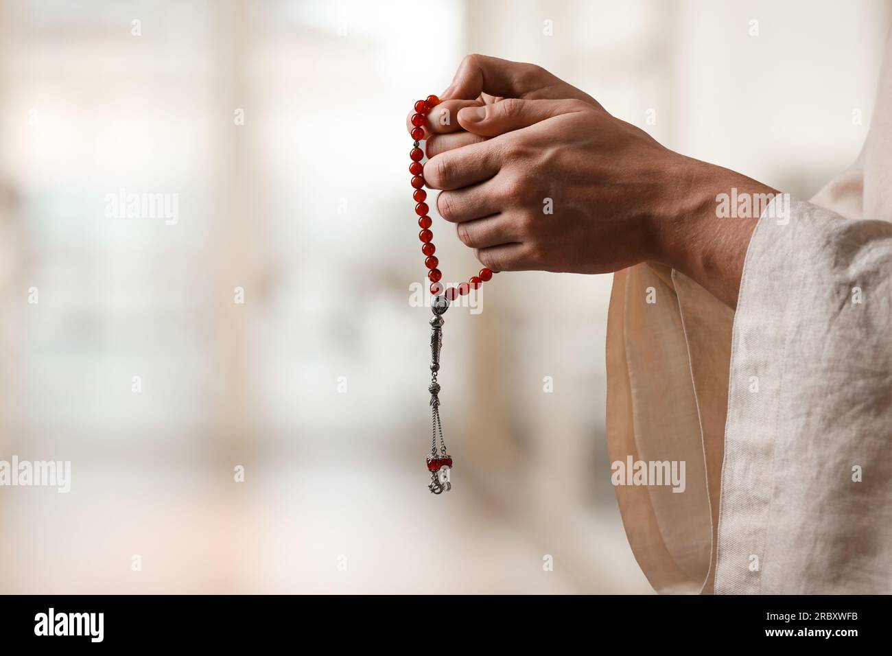 Muslim man with misbaha praying on blurred background, closeup. Space ...