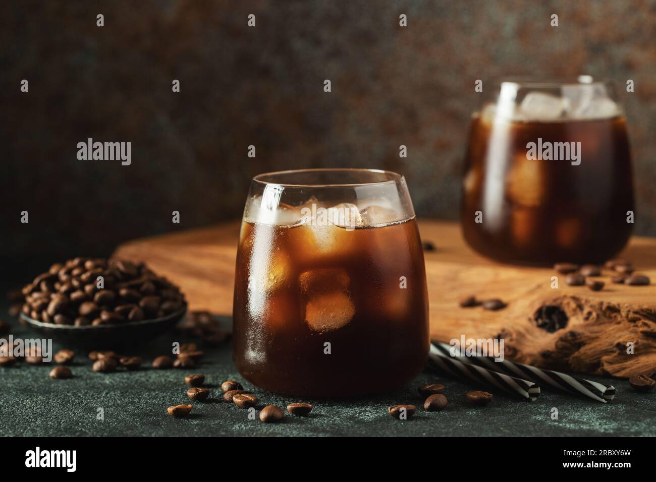 Ice coffee in a tall glass with cream poured over, ice cubes and beans ...