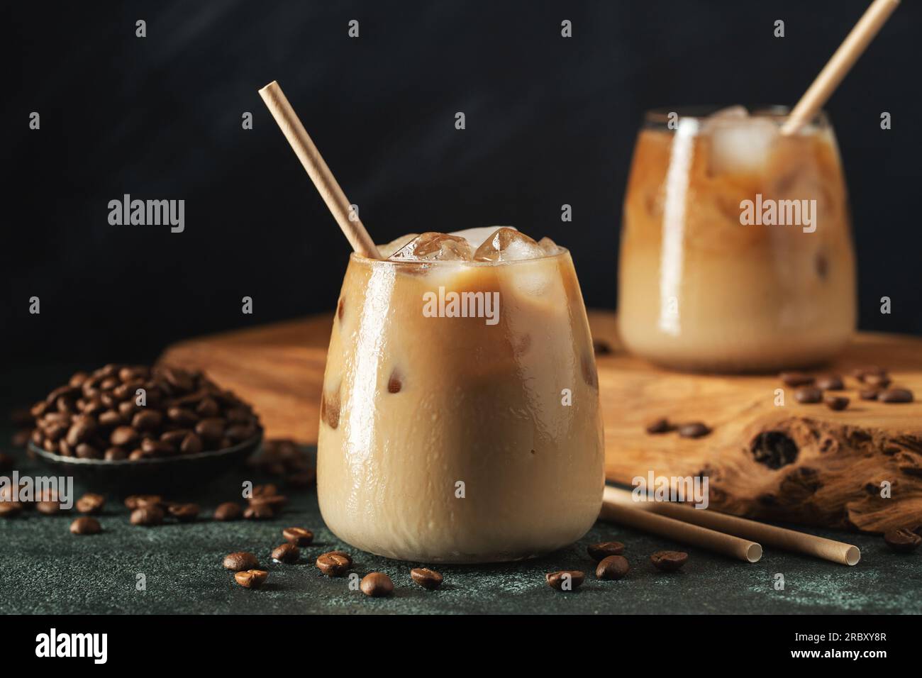 Ice coffee in a tall glass with cream poured over, ice cubes and beans ...