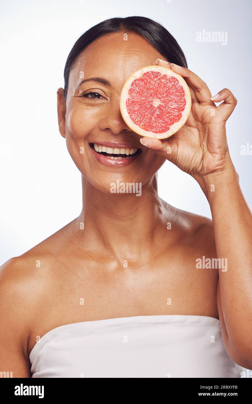 Skincare, face and mature woman with grapefruit in studio isolated on a white background ...