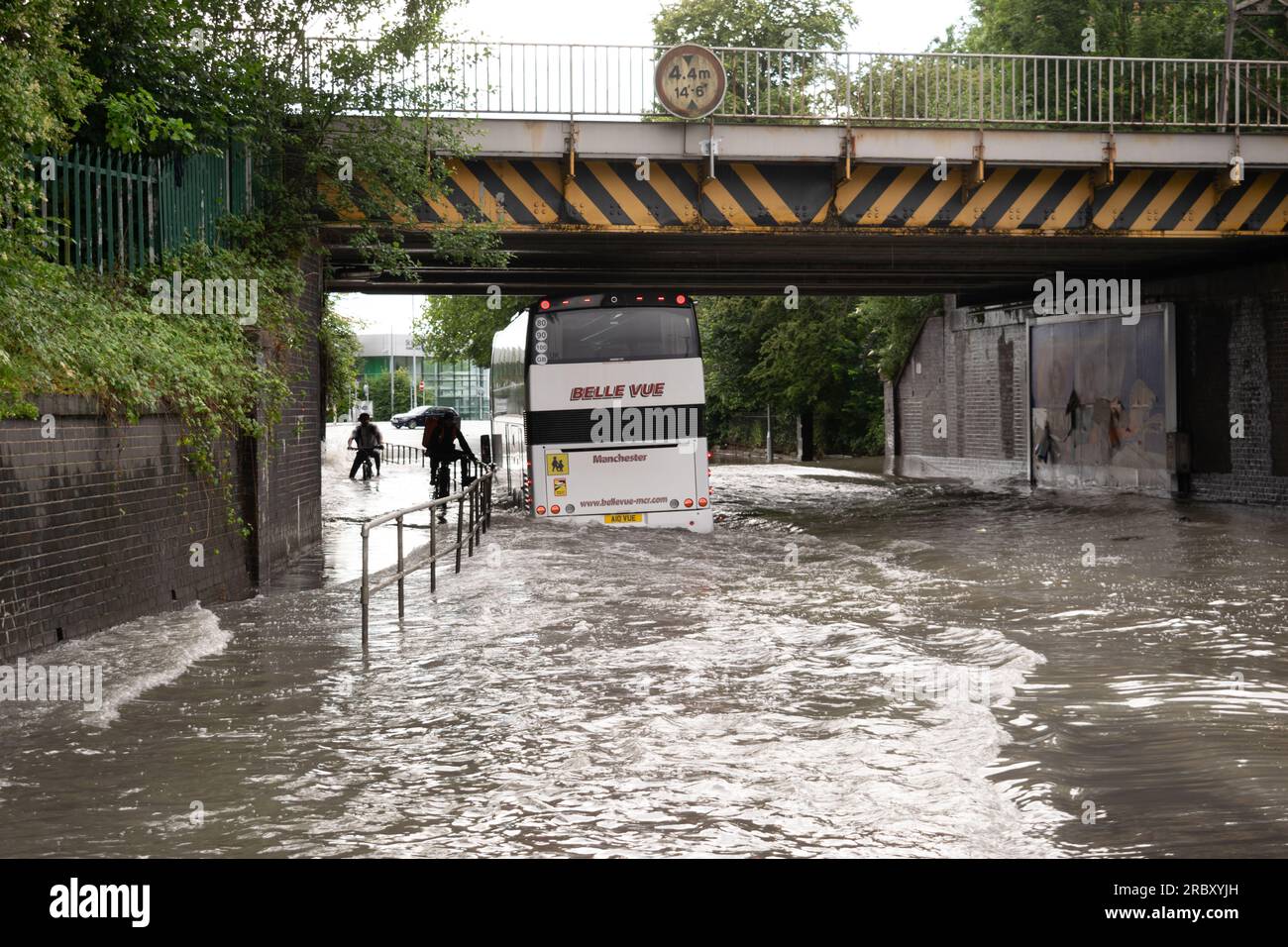 Bus driving through flood water on Road during storm. Cyclist holding ...