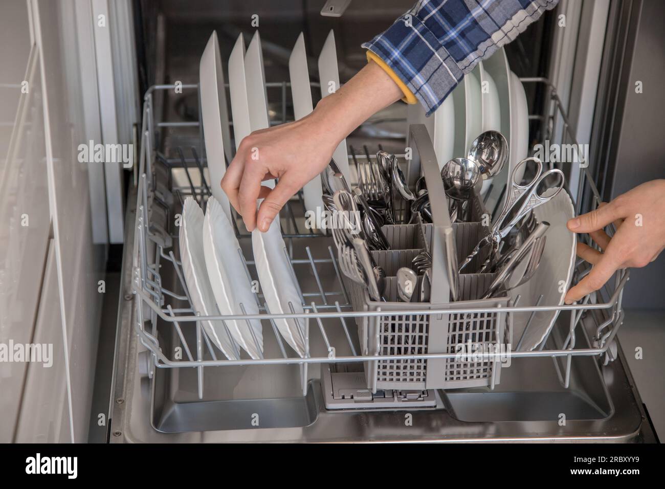 Dishwasher open and a person removing the washed dishes. Concept of ...