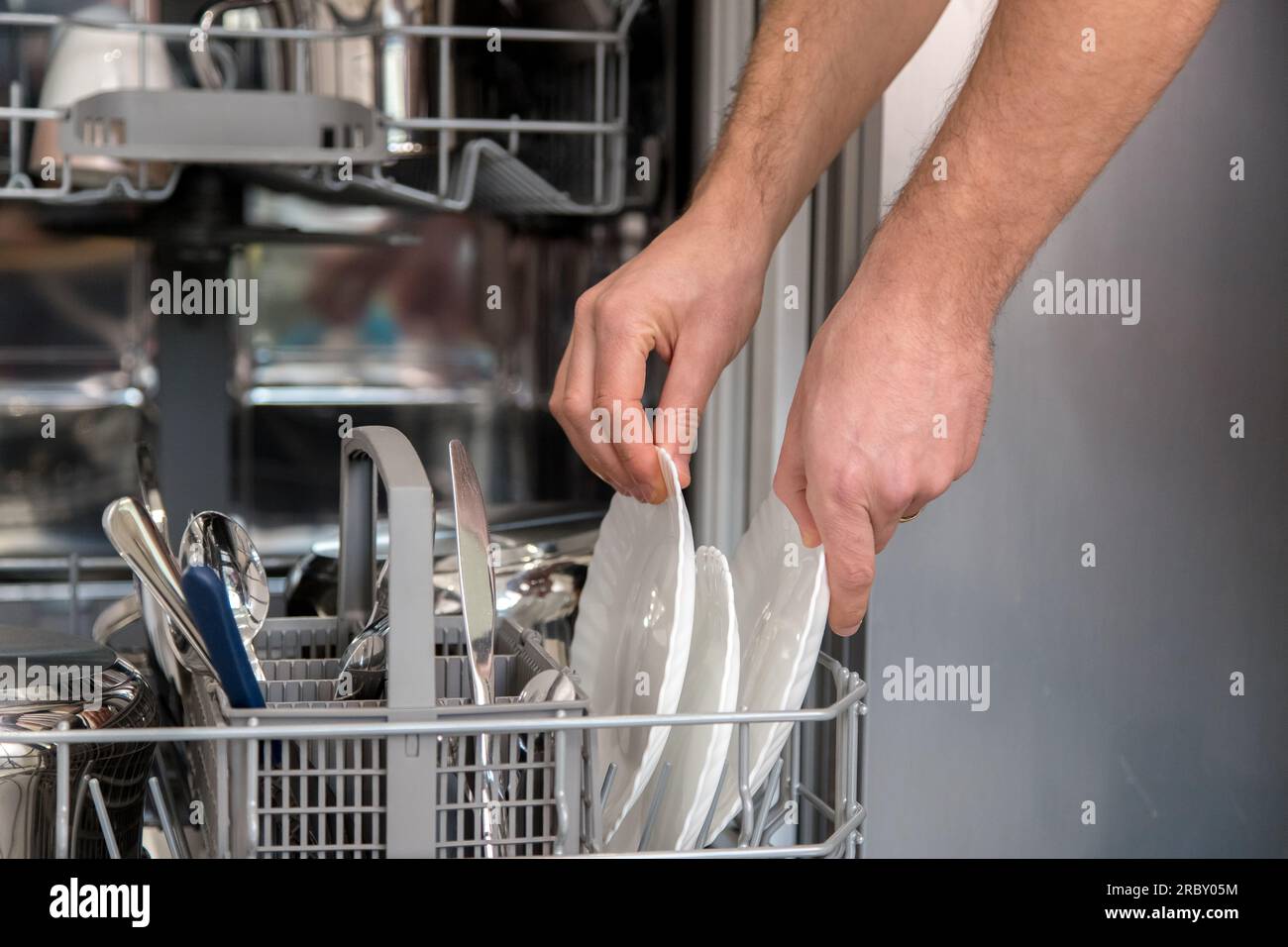 Dishwasher open and a person removing the washed dishes. Concept of ...