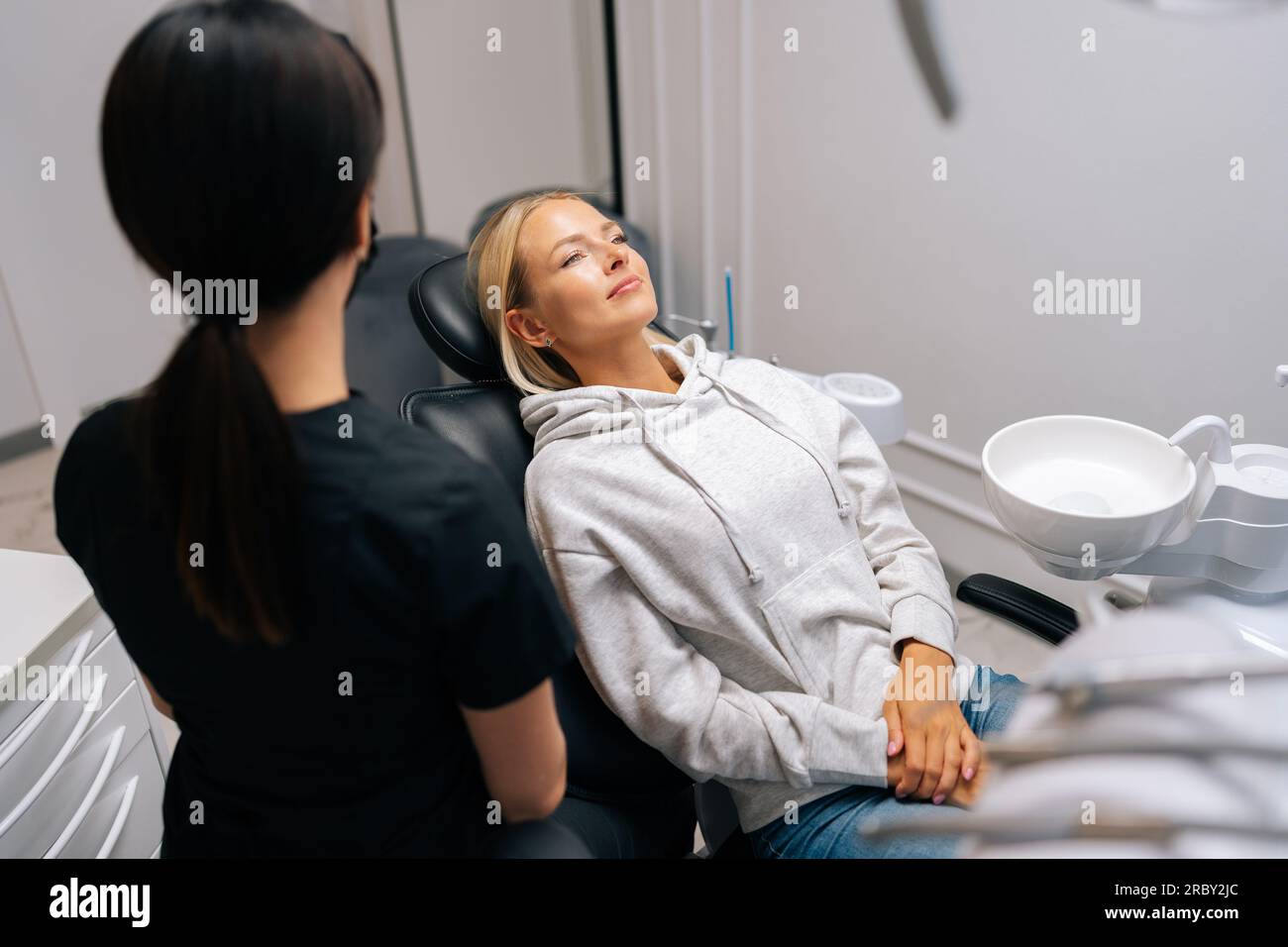 Remote back view of young blonde woman with toothache lying on dental ...