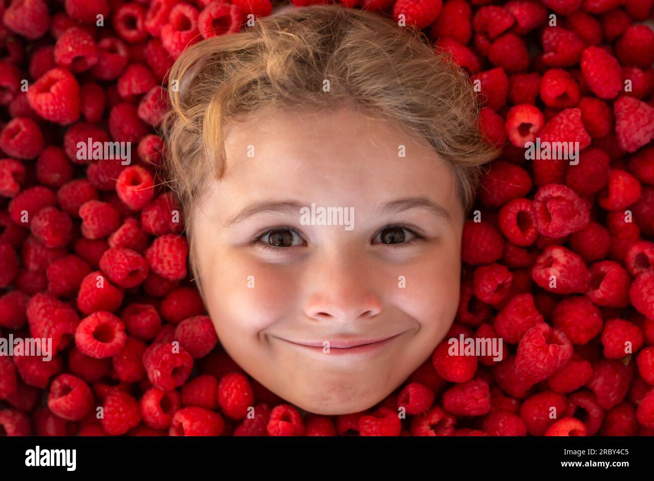 Happy little child face with raspberry. Child picking raspberry. Kids ...