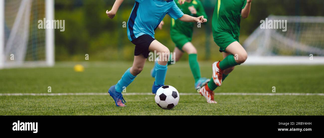 Junior level soccer competition between players running and kicking ...
