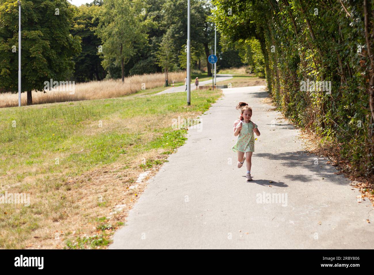Little girl running on a path in the park on a sunny day Stock Photo ...