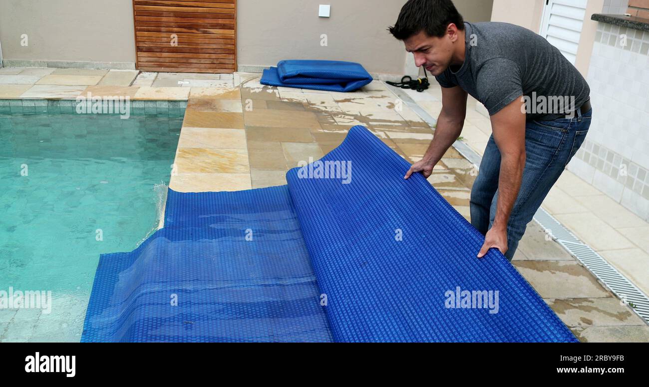 Man removing swimming pool cover and folding protector Stock Photo - Alamy