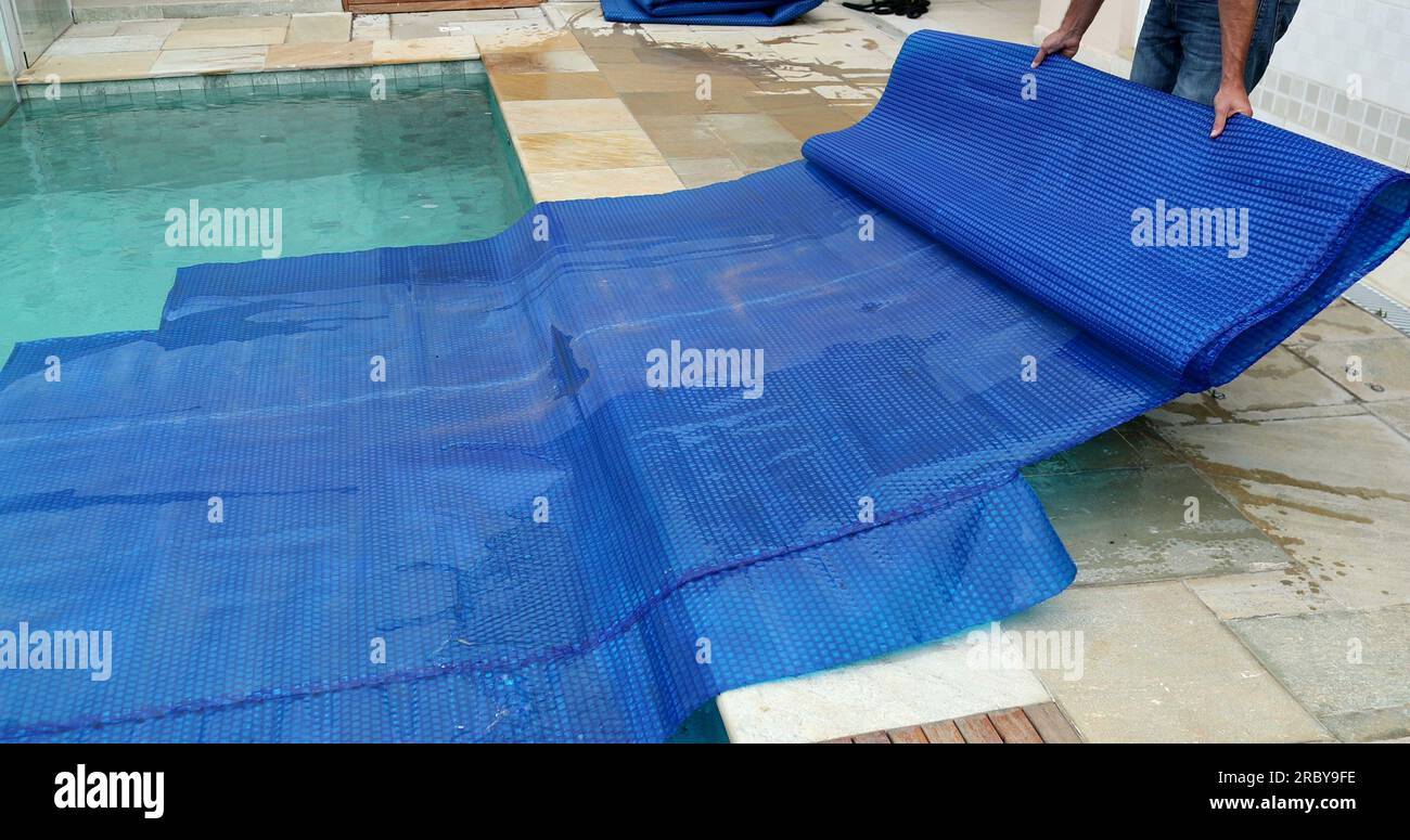 Man removing swimming pool cover and folding protector Stock Photo - Alamy