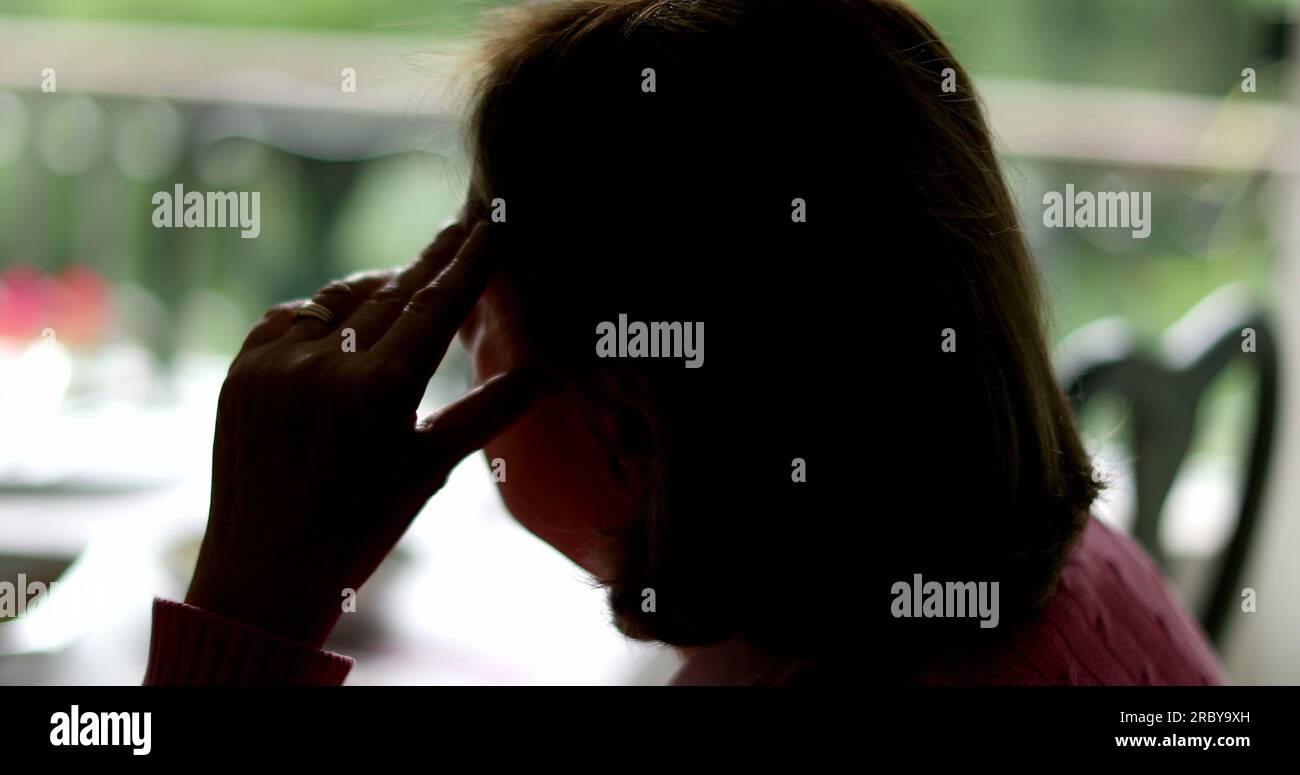 Silhouette of pensive older woman thinking back of contemplative person ...