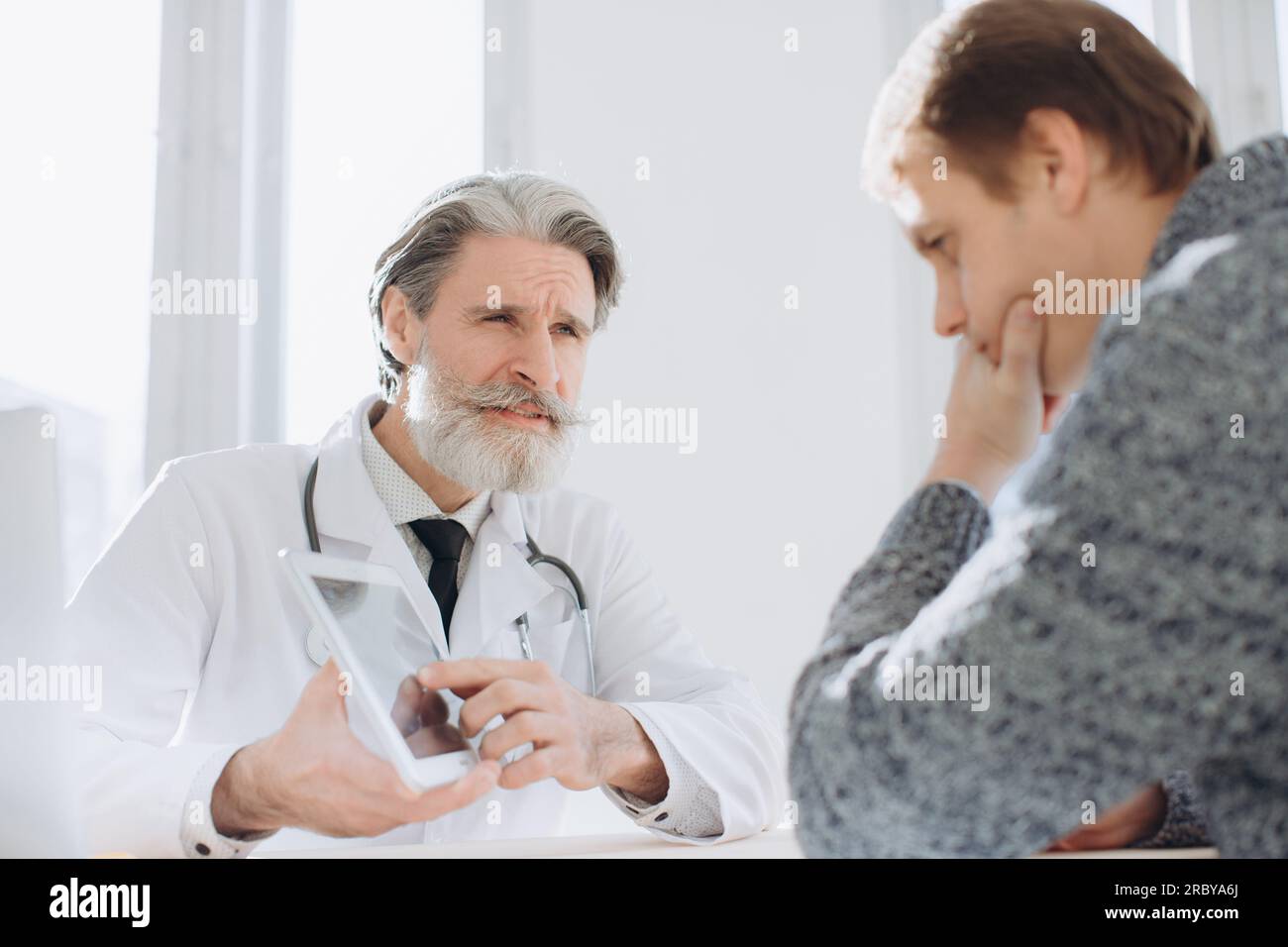 Senior doctor giving advices to a man Stock Photo - Alamy