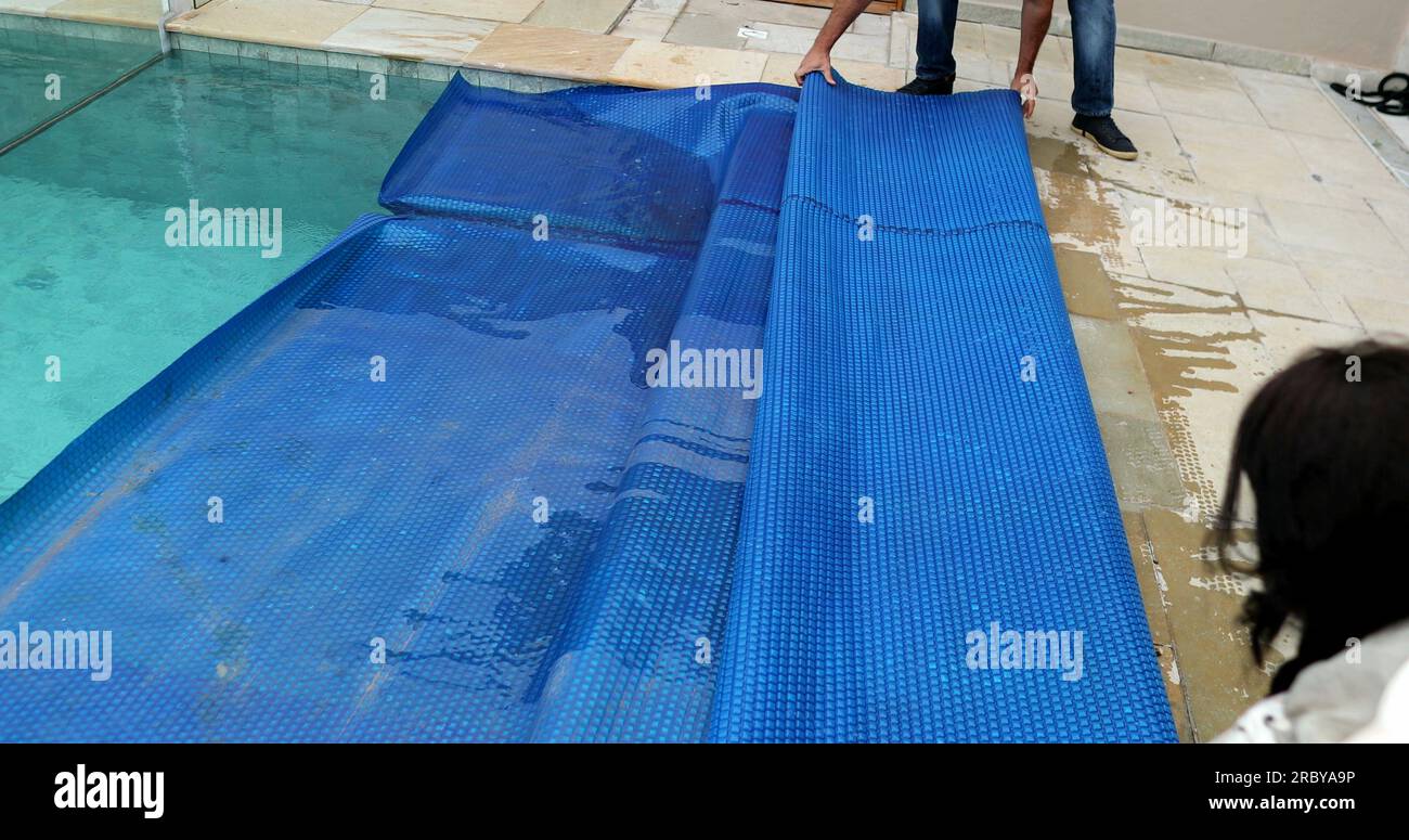People removing swimming pool cover and folding pool protector Stock ...