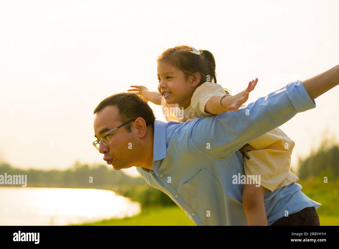 Happy father holding daughter on back playing together in garden Stock ...
