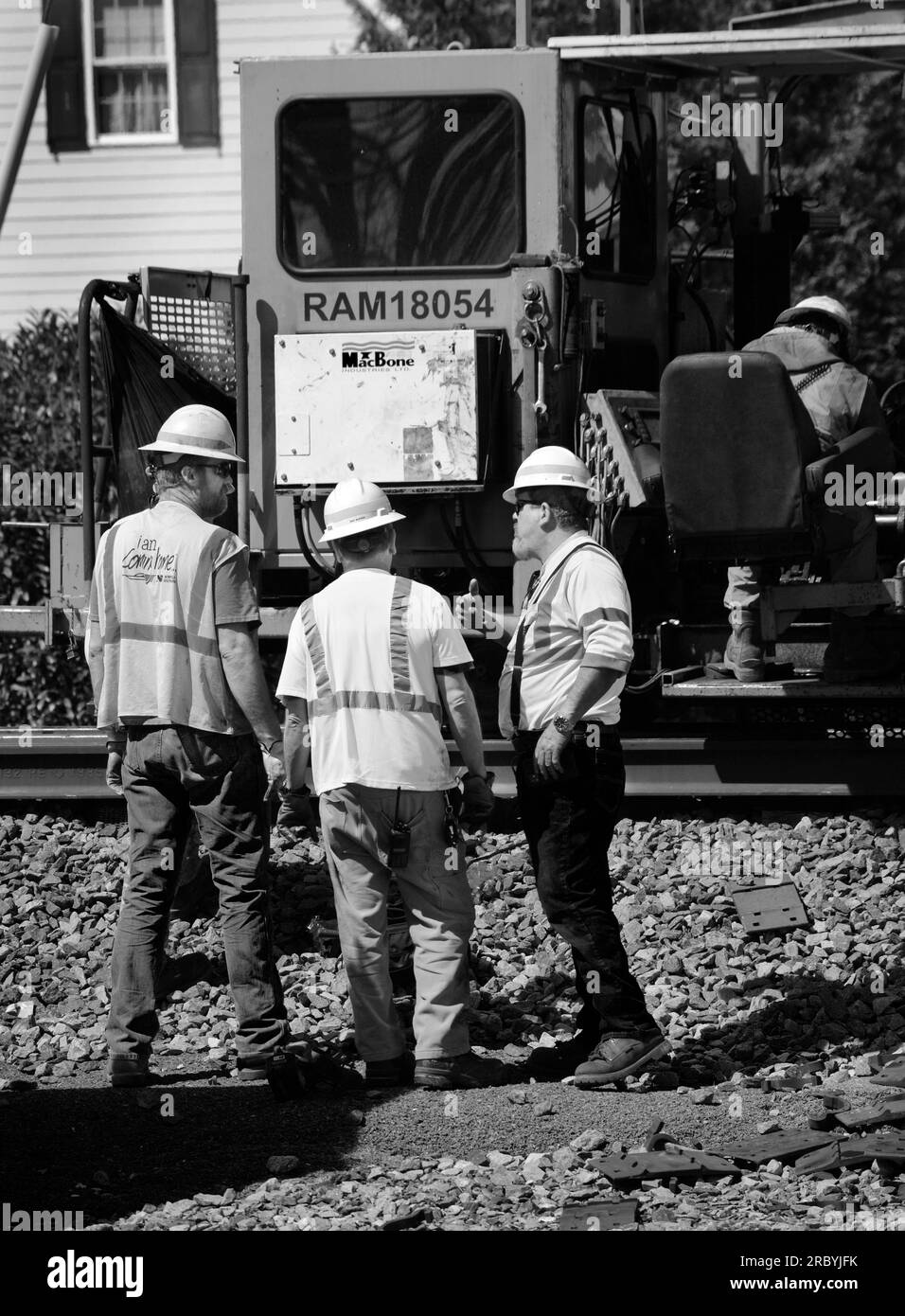 Three railroad workers discuss a repair job beside the tracks in ...