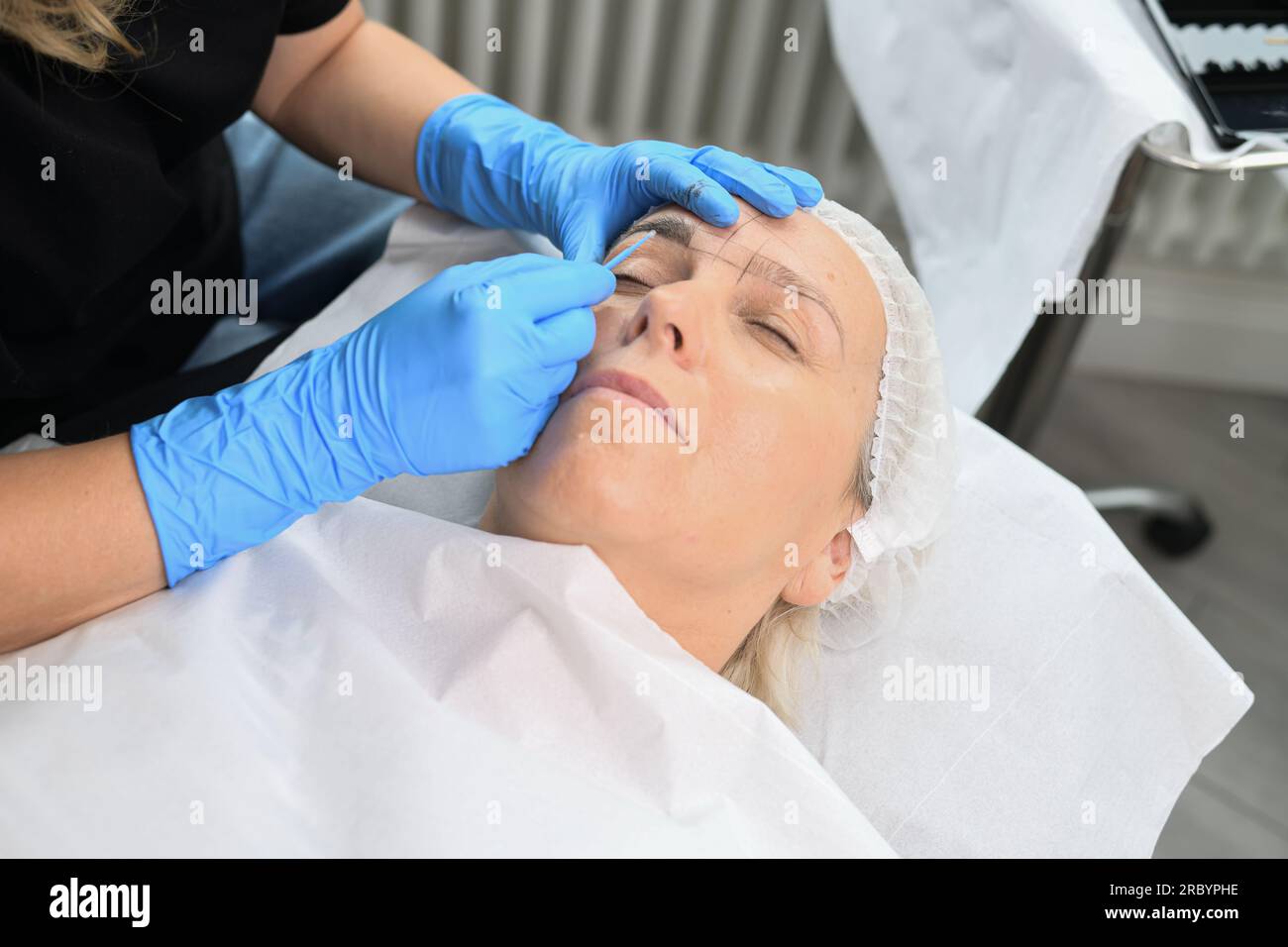 Microblading close-up, hands adding pigment to eyebrows, woman head ...