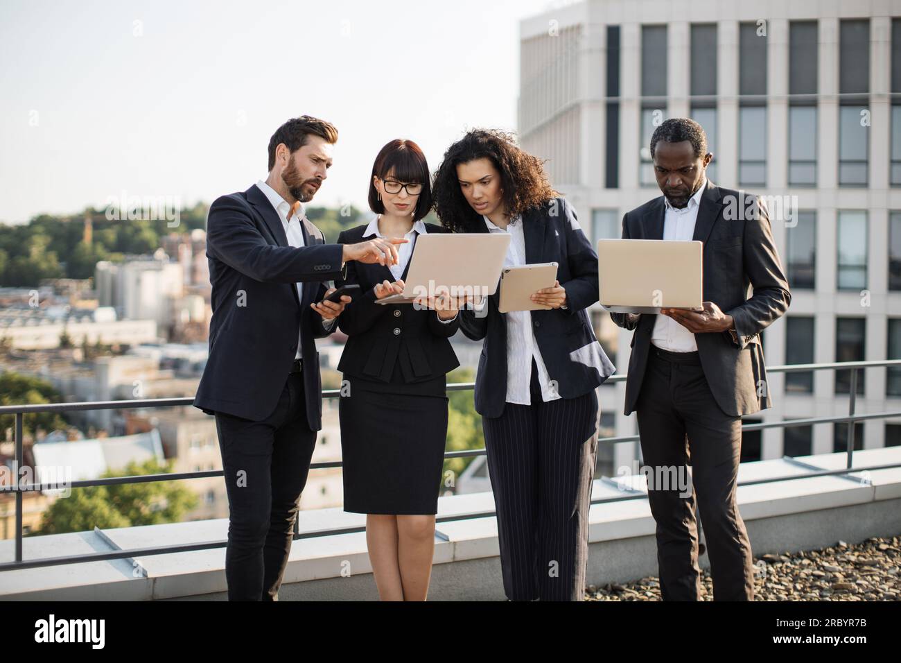 Multicultural team of developers using remote devices and discussing ...