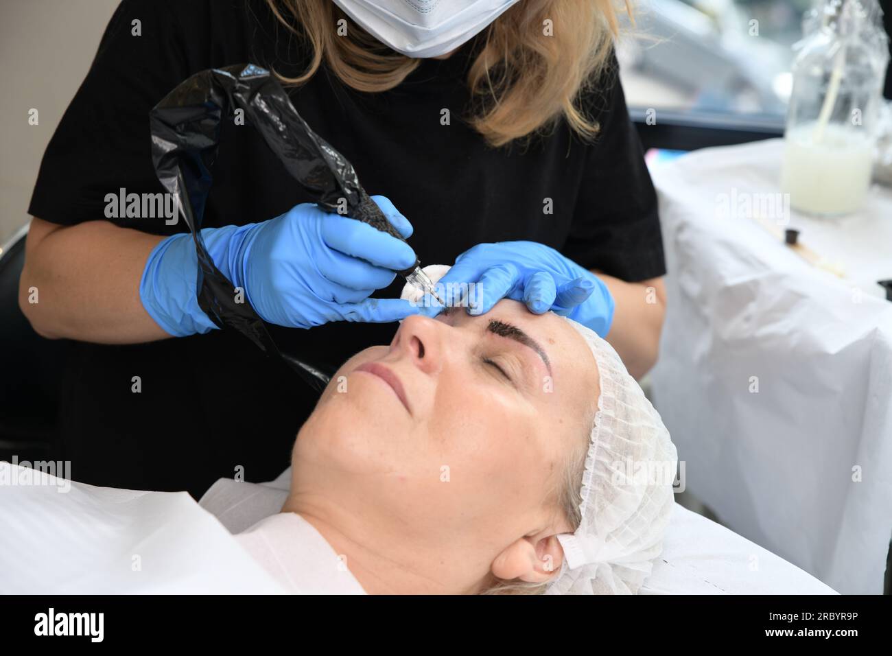 Microblading close-up, hands adding pigment to eyebrows, woman head ...