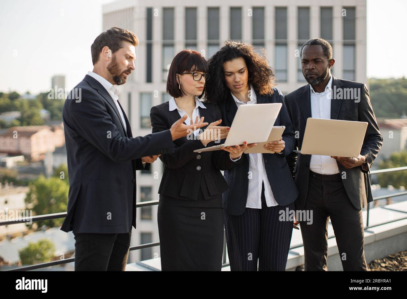 Multicultural team of developers using remote devices and discussing ...