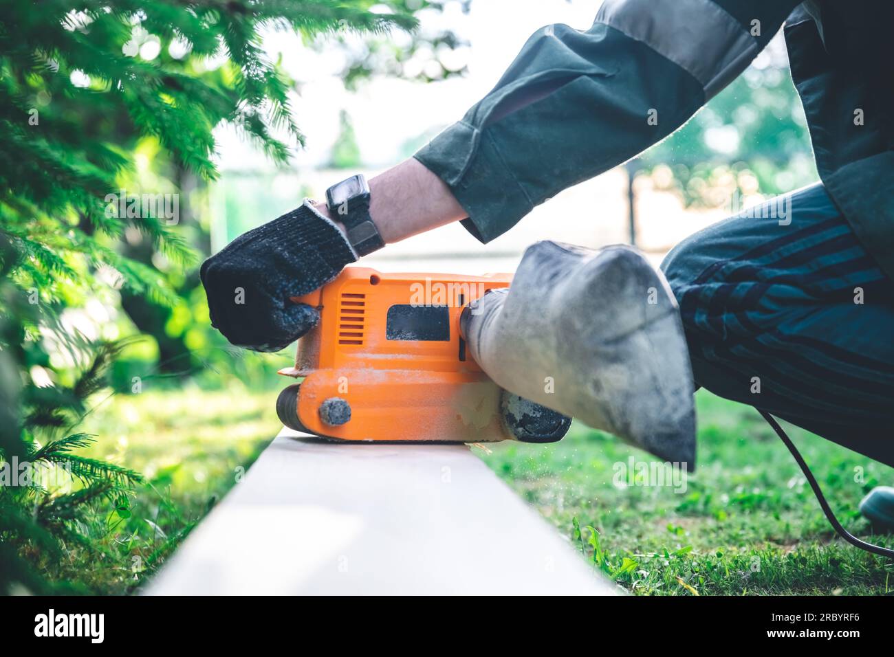 The man grinds the boards with a belt grinder, the electric tool for ...