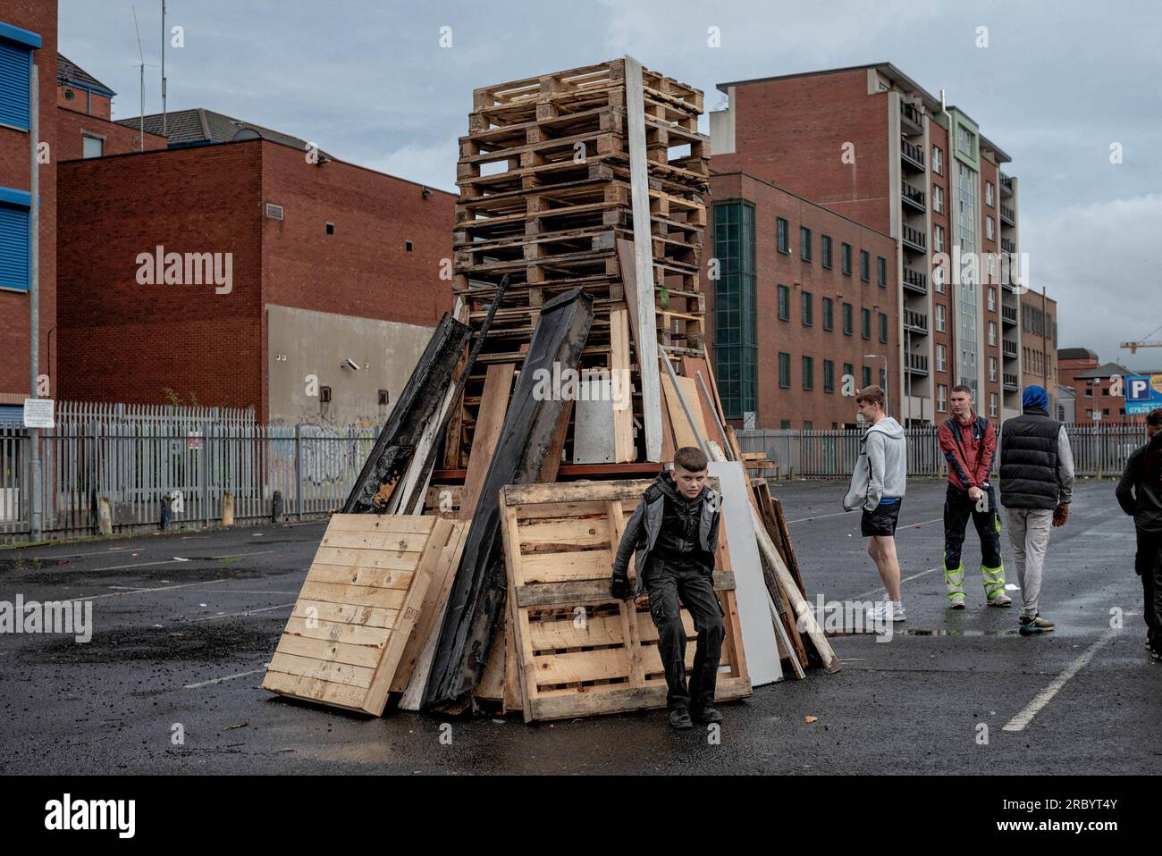 Youths stand next to wooden pallets meant for a bonfire. Eleventh Night ...