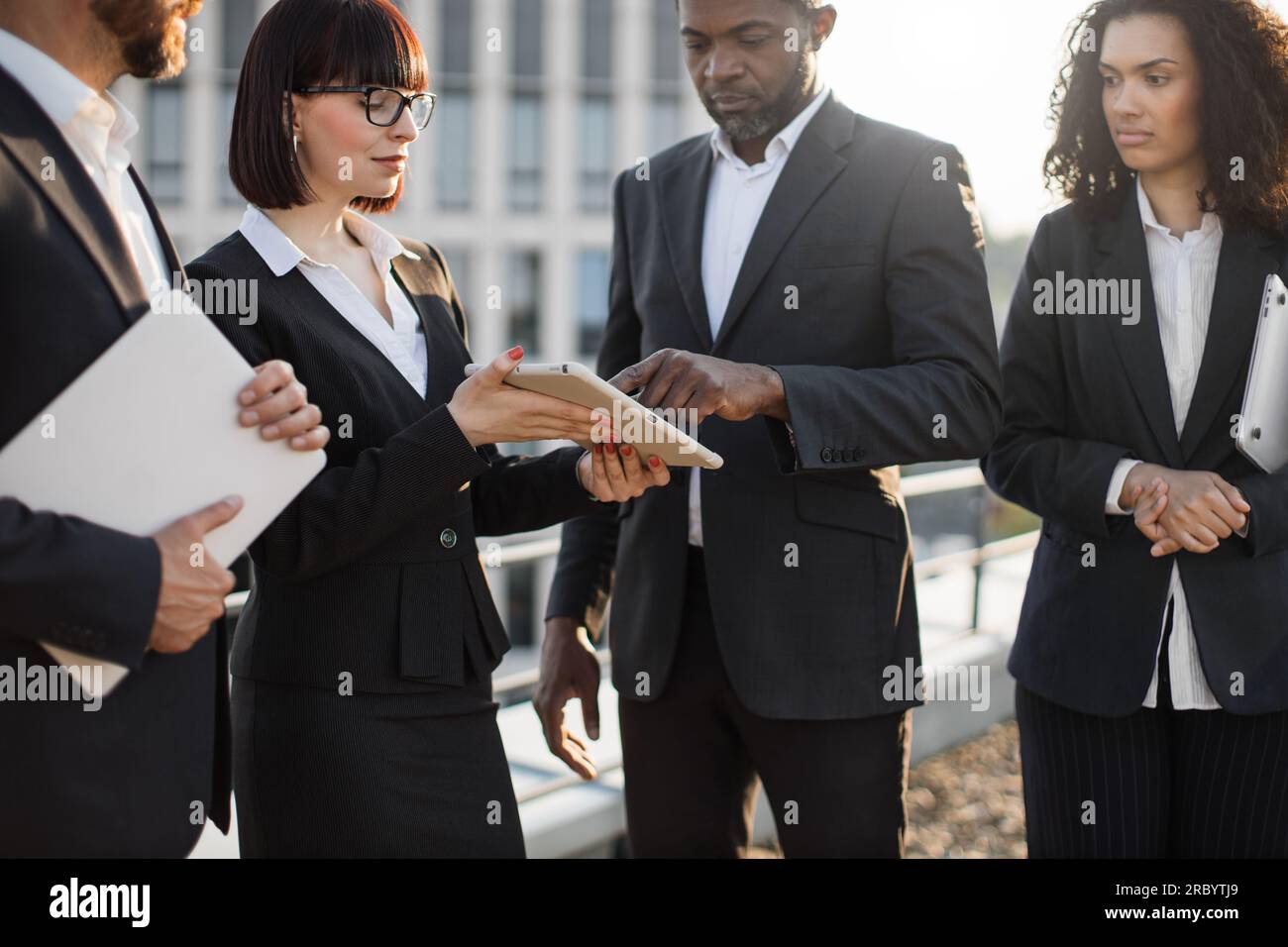 Crop of four multiracial colleagues in suits signing contract during ...