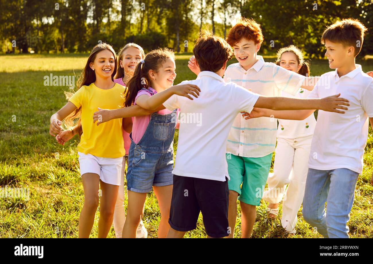Group of happy children meet, hug and play together in a green park in ...