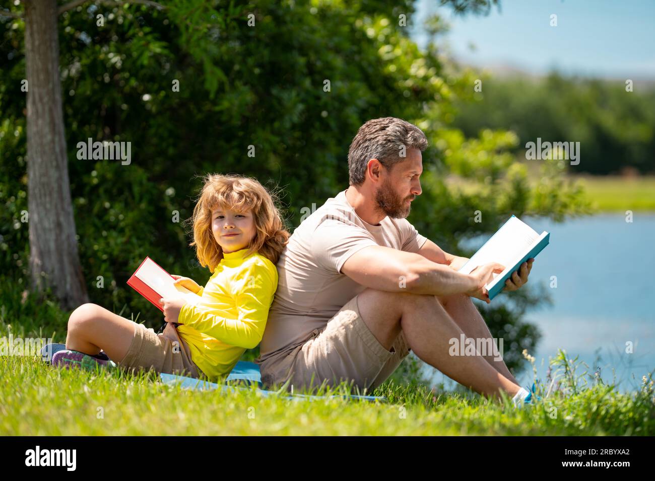 Father read a book with son in a park outdoors. Father and child son ...