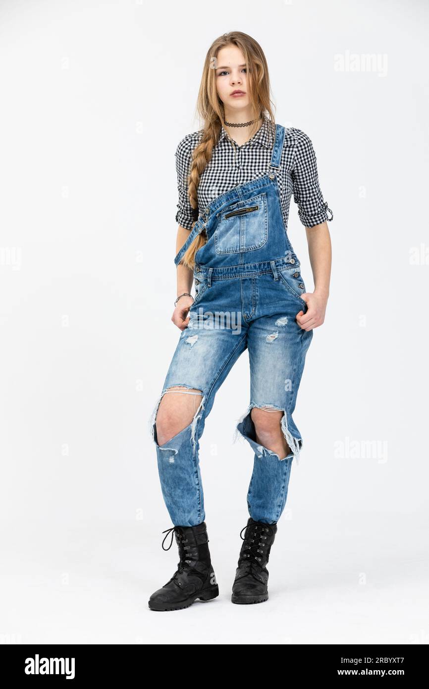 A girl dressed in ragged jeans poses for a photo shoot against a white ...