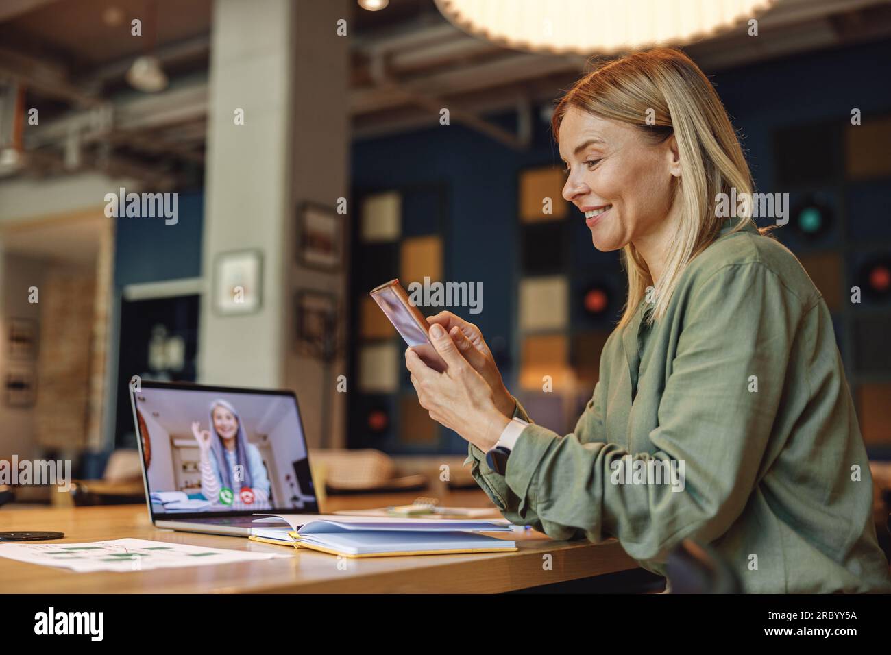 Smiling business woman is using phone during video conference in ...