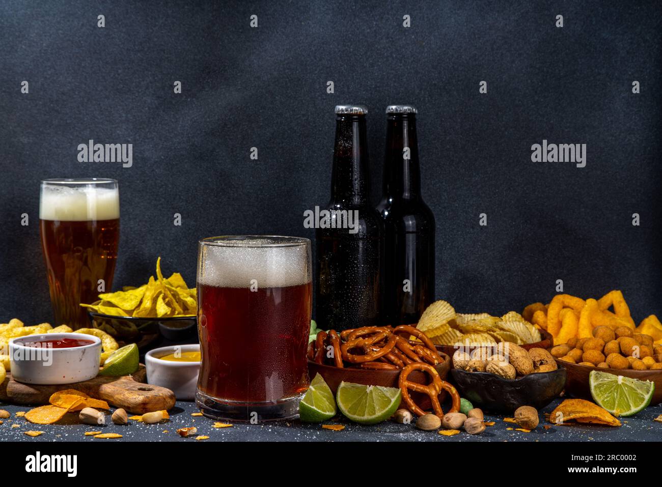 Beer with various salted snacks set. Black table background with ...