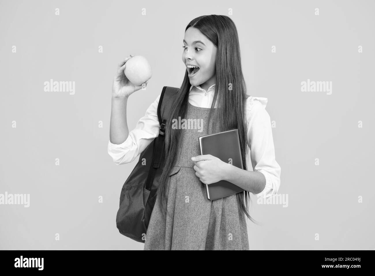 Excited face. School girl hold copybook and book on yellow isolated ...