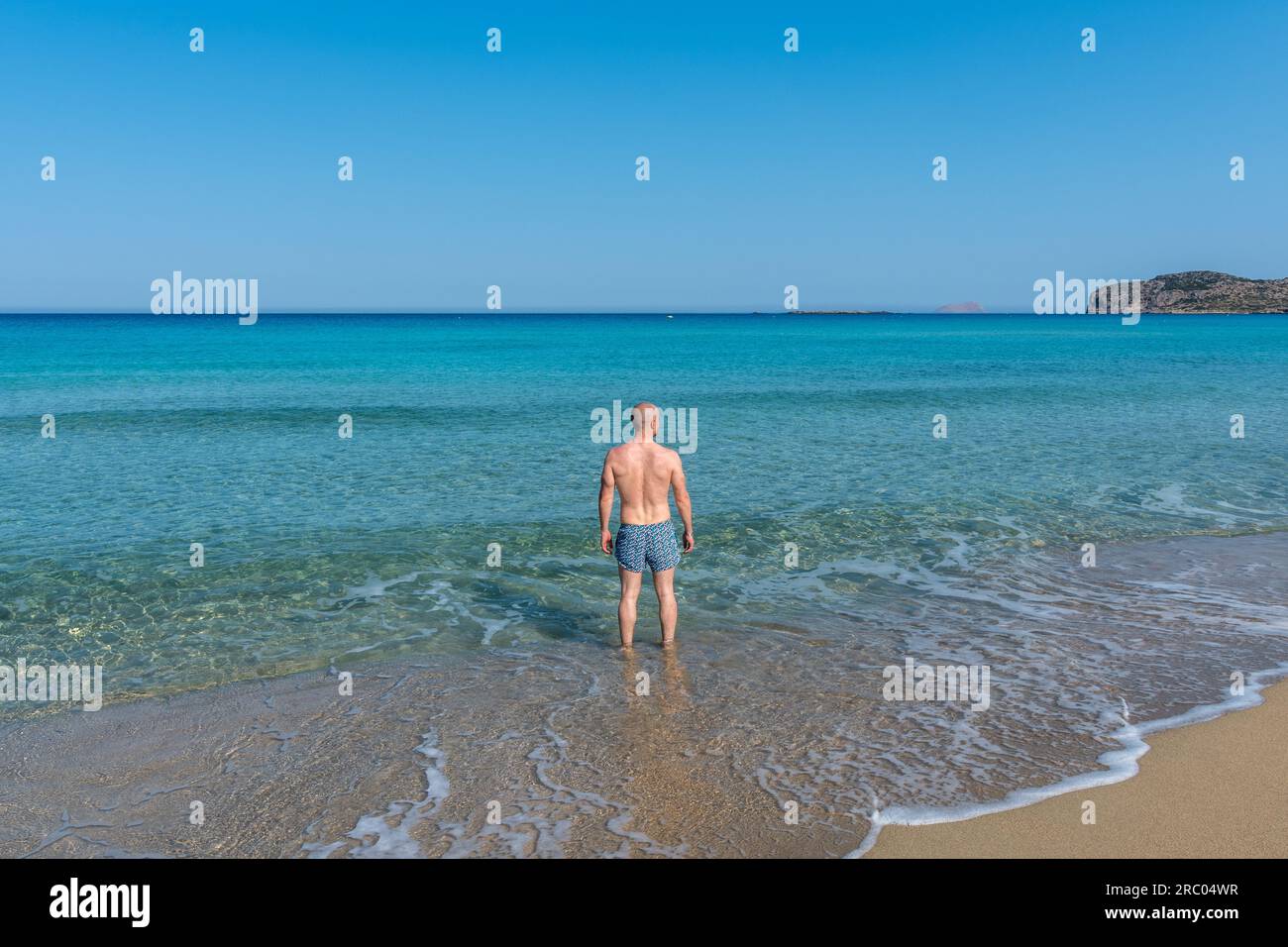 View of the turquoise ocean from the beach with a boy in a bathing suit ...