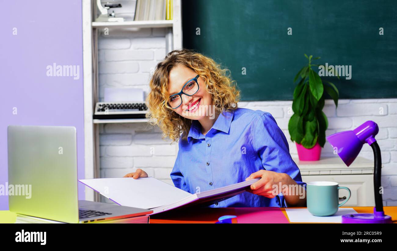 Smiling female teacher or student in classroom. Female teacher sitting ...