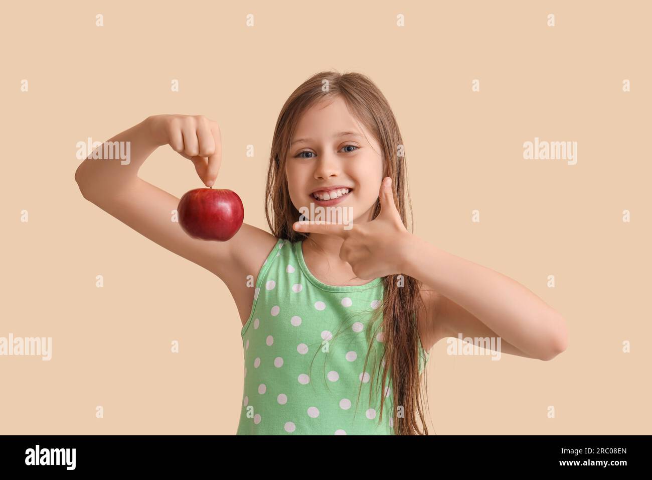 Little girl pointing at apple on beige background Stock Photo - Alamy
