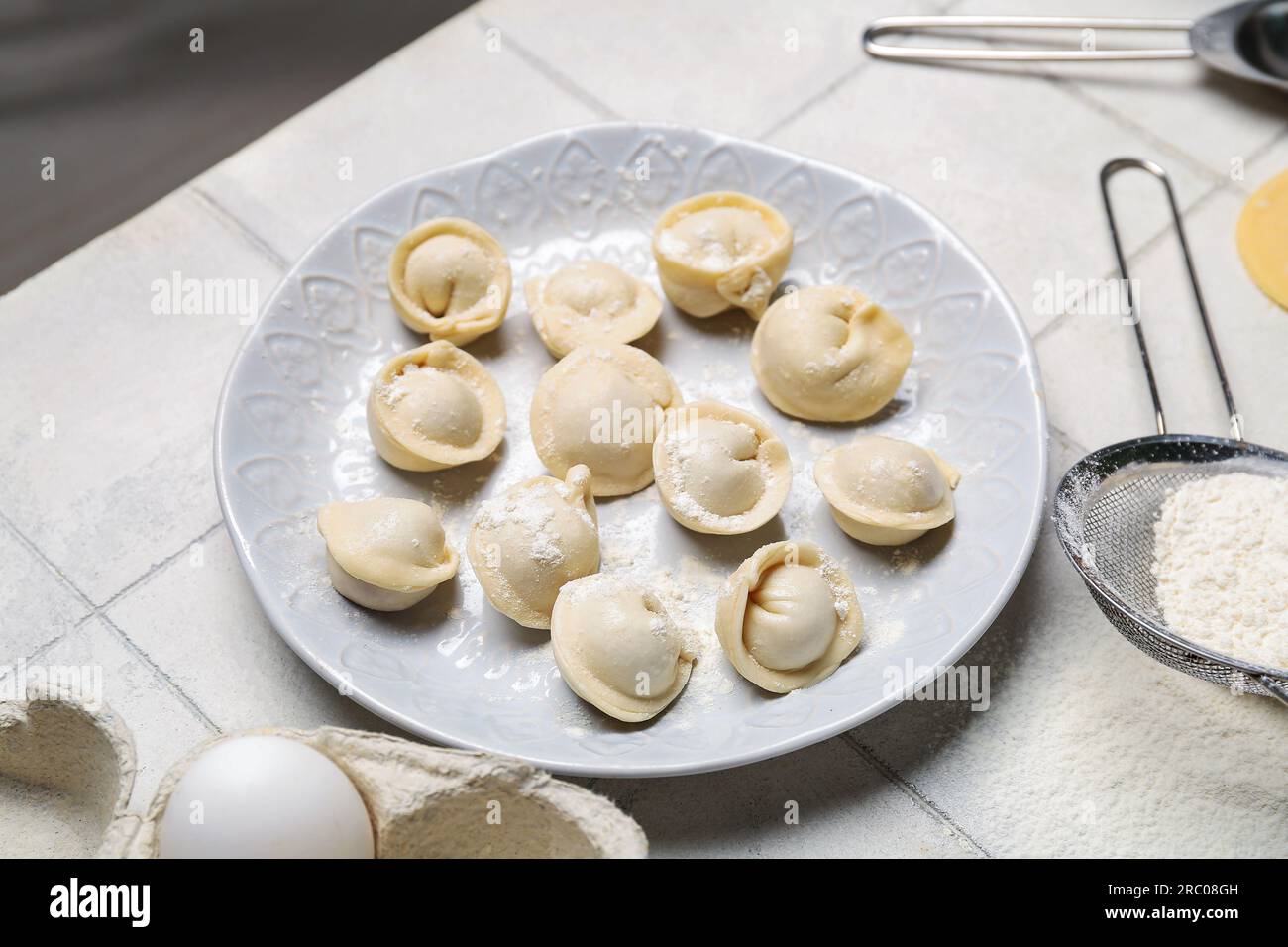 Plate with uncooked dumplings on white tile background Stock Photo - Alamy
