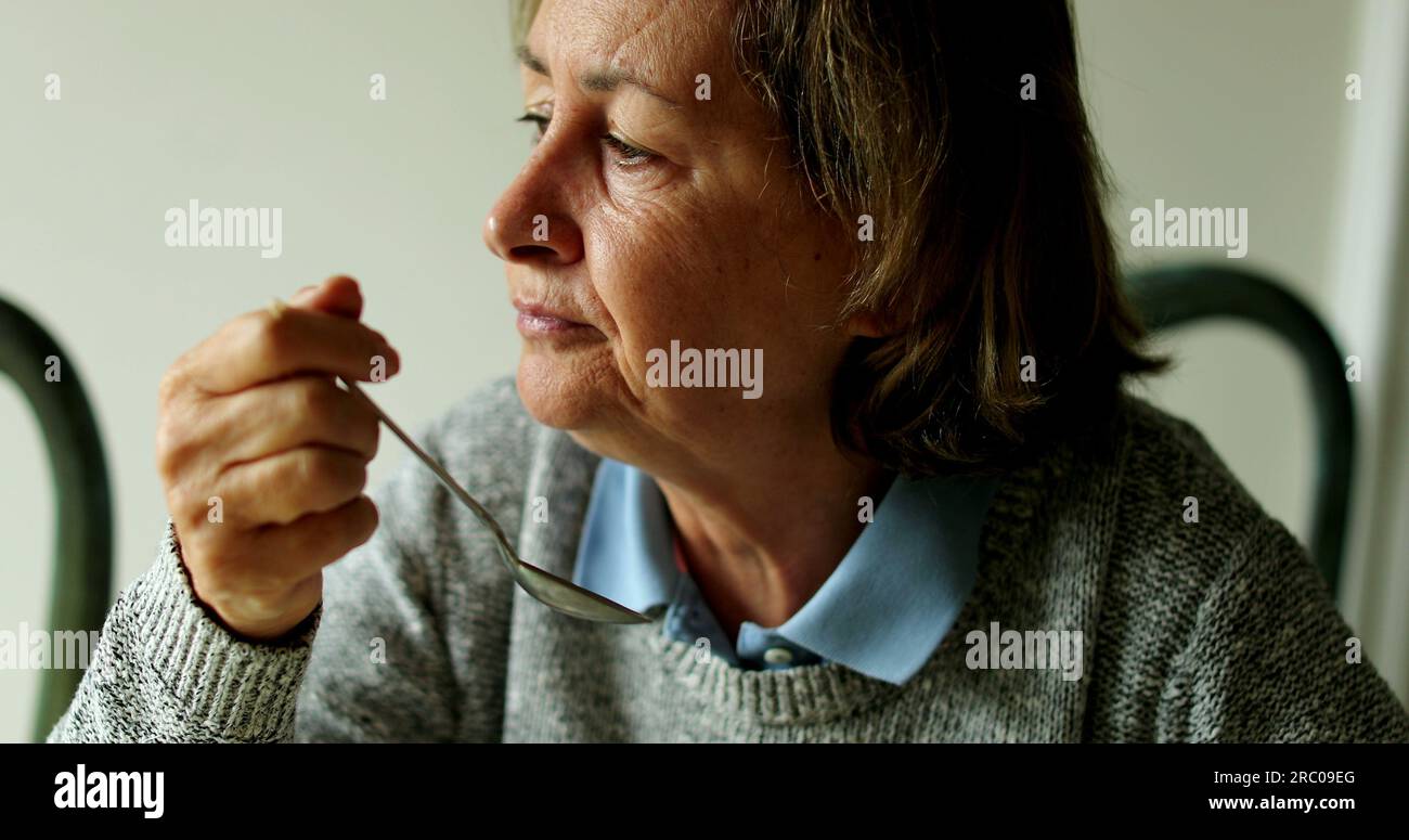 One thoughtful senior woman thinking while eating lunch Stock Photo - Alamy