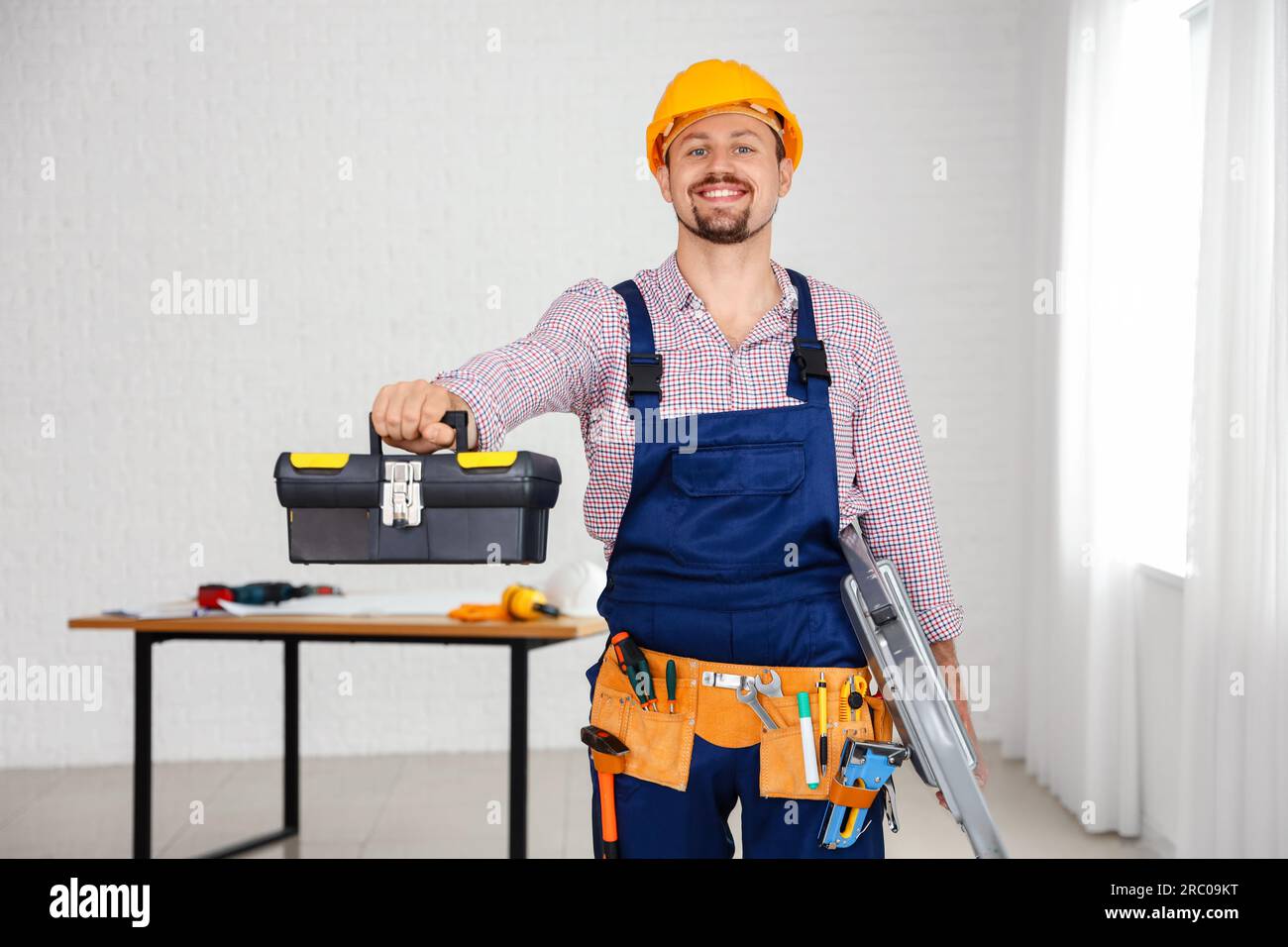 Male builder with tool bag and stepladder in room Stock Photo - Alamy