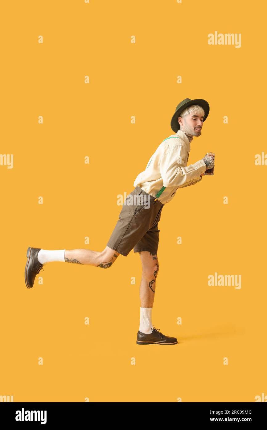 Young tattooed man in traditional German clothes with beer dancing on ...