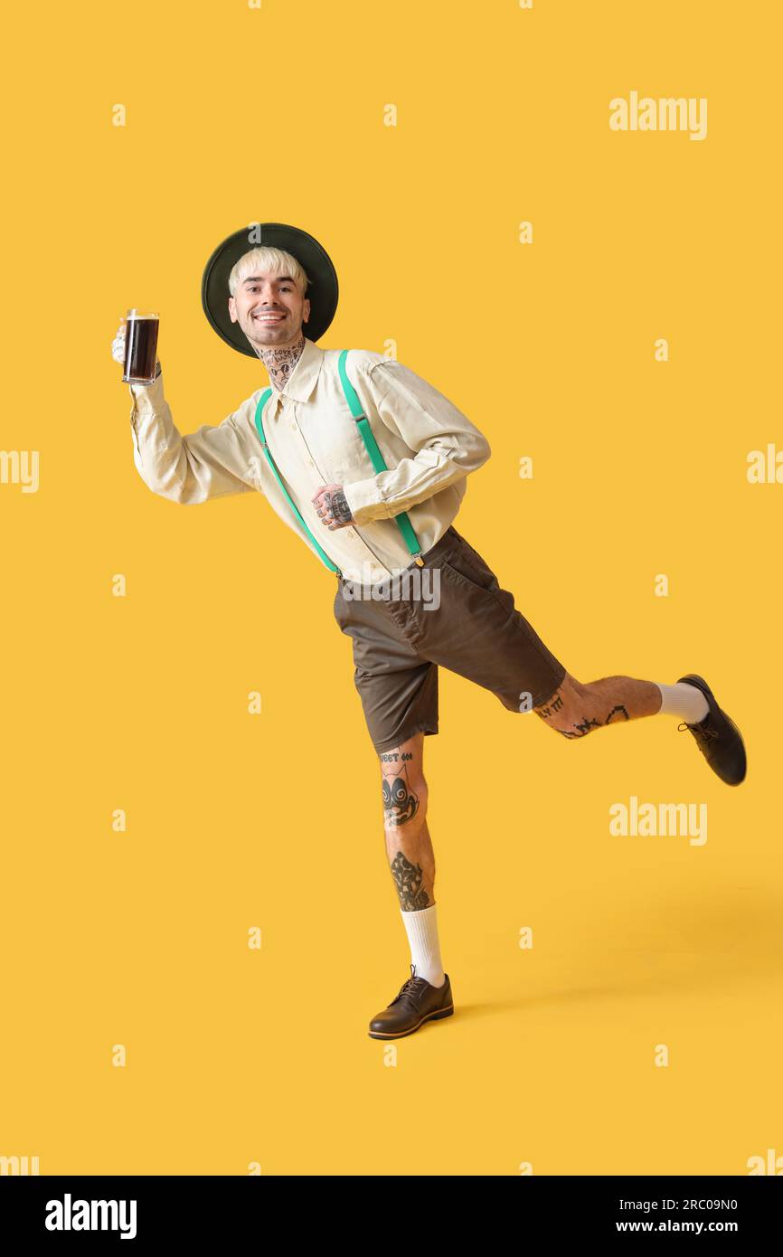 Young tattooed man in traditional German clothes with beer dancing on ...