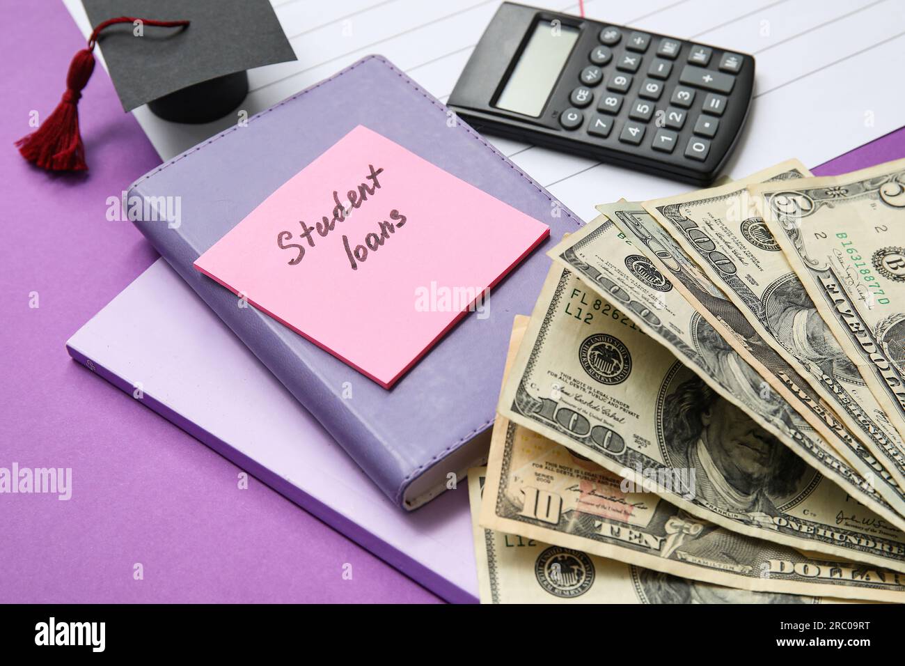Sticky note with text STUDENT LOANS, calculator, notebook, dollar ...